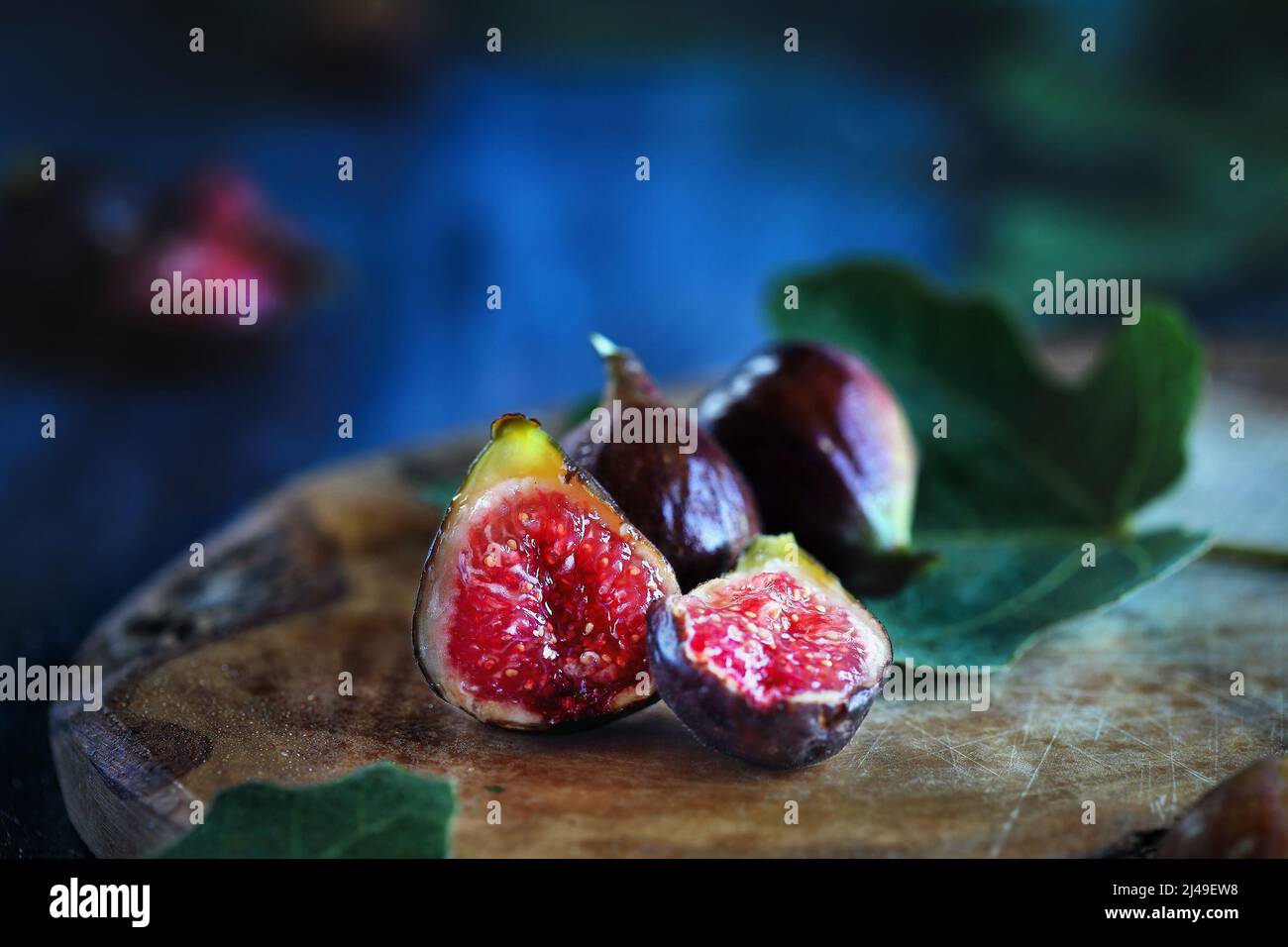 Whole and sliced fresh figs over a rustic cutting board background with ...