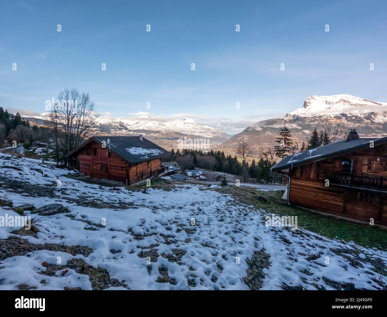 Typical wooden chalet in winter with mountains and blue sky background ...