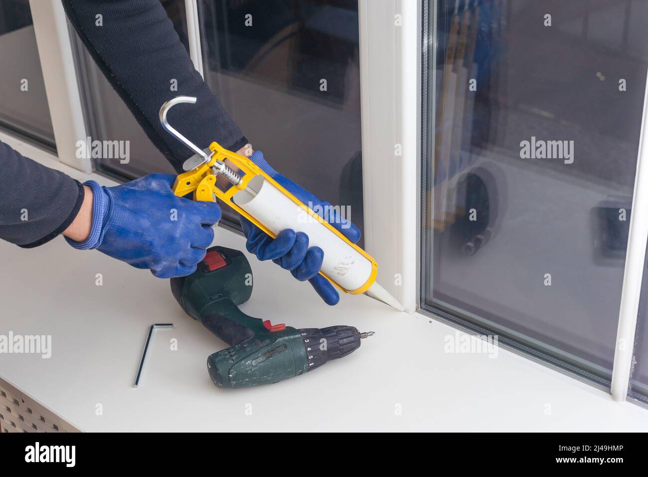 Worker is applying polyurethane foam to fill gap between sash and ...