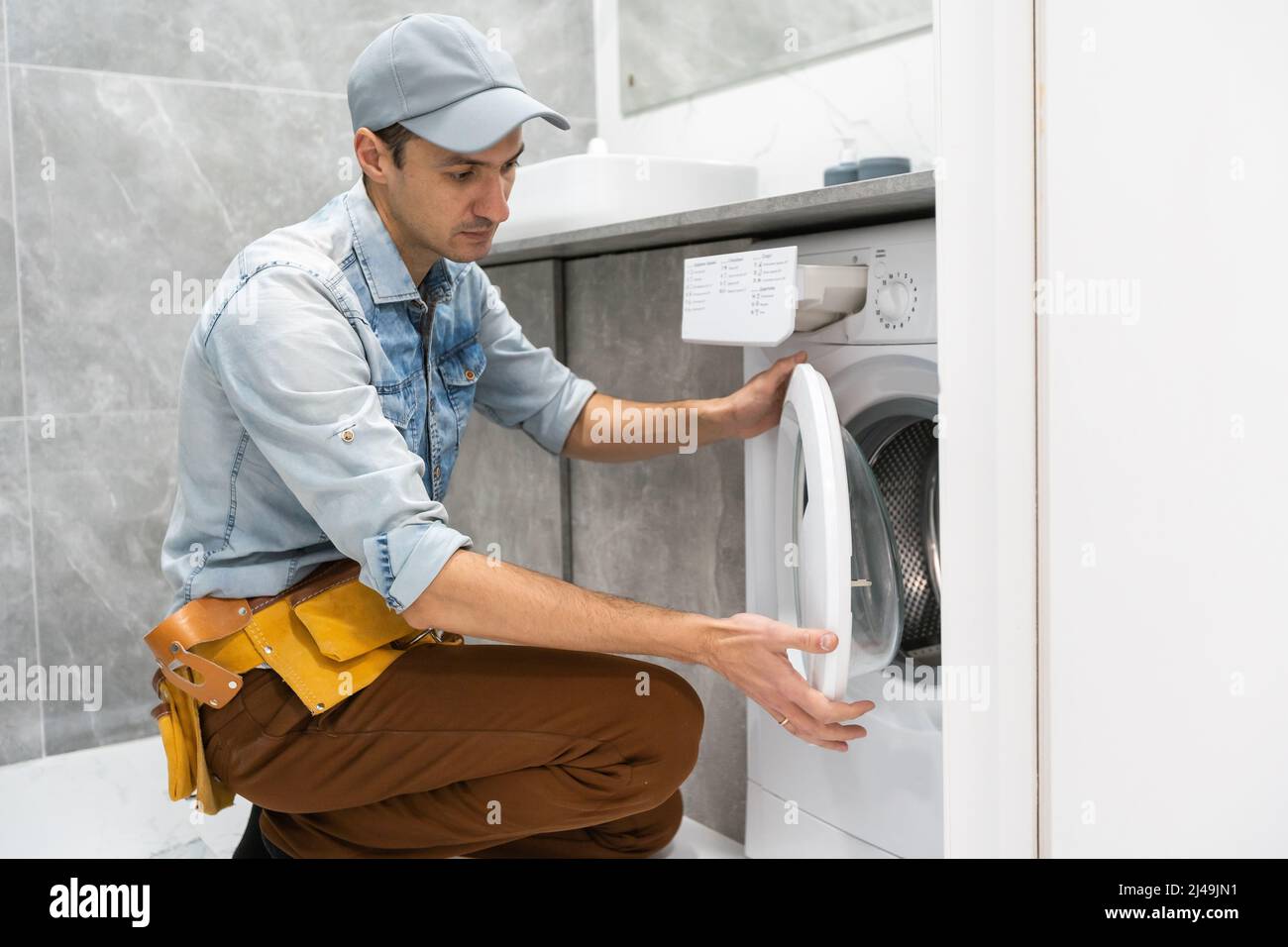 The young handsome repairman in worker suit with the professional tools ...