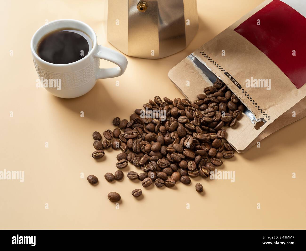Cup of freshly brewed coffee and roasted beans on a beige background ...