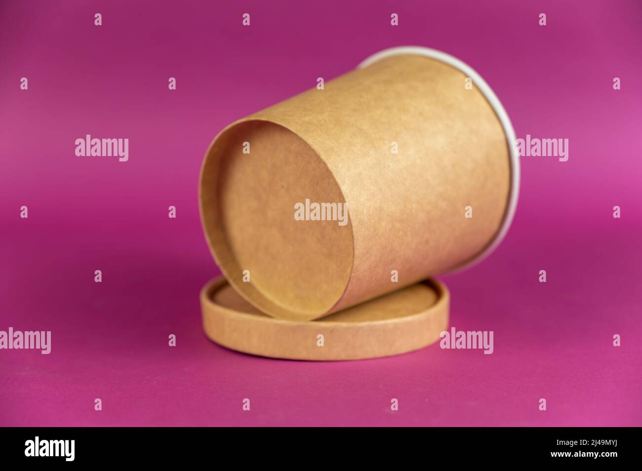 Empty cylindrical paper container with lid opposite-colored background ...