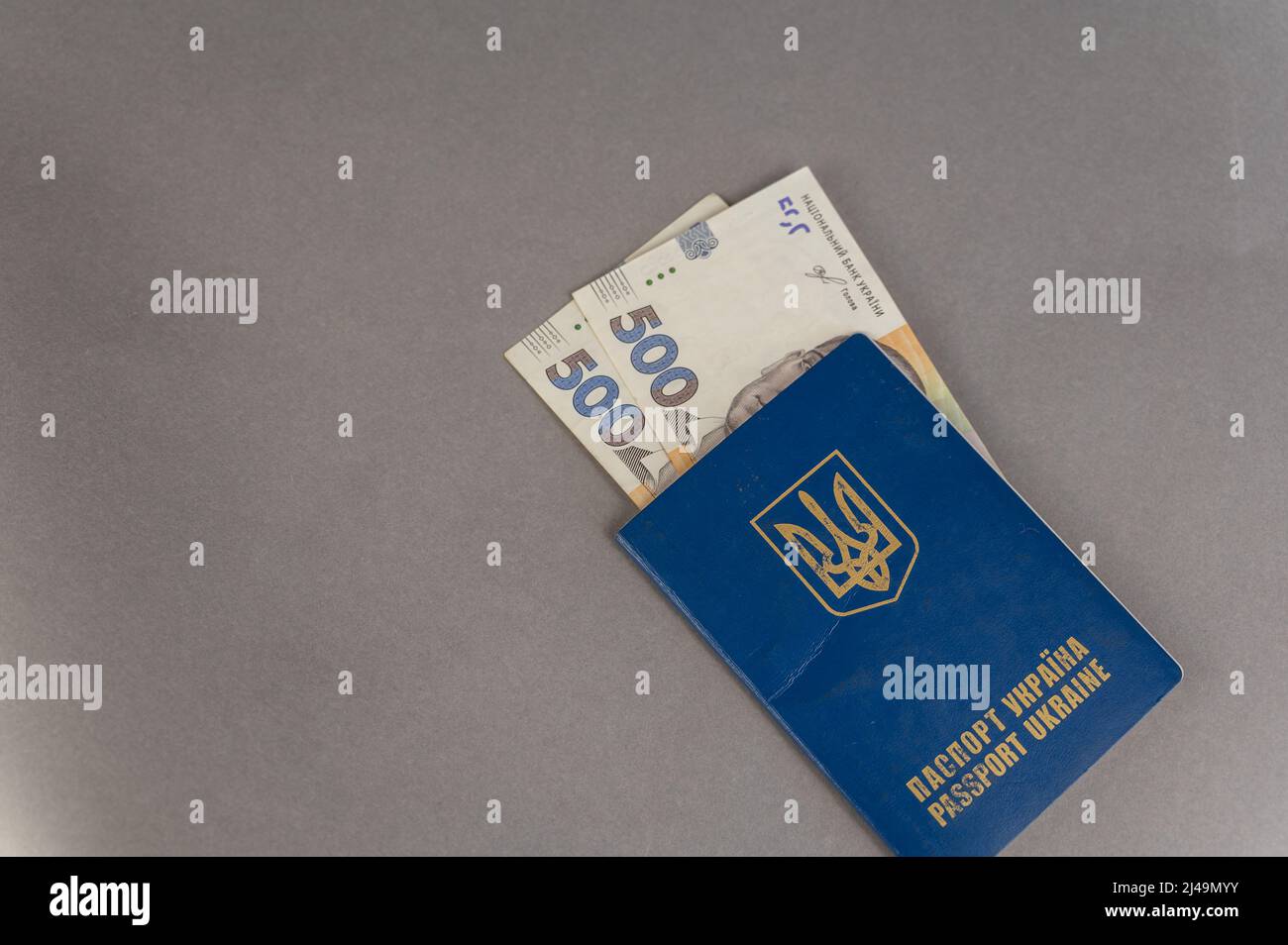 A blue covered passport and cash against a gray background. Ukrainian ...