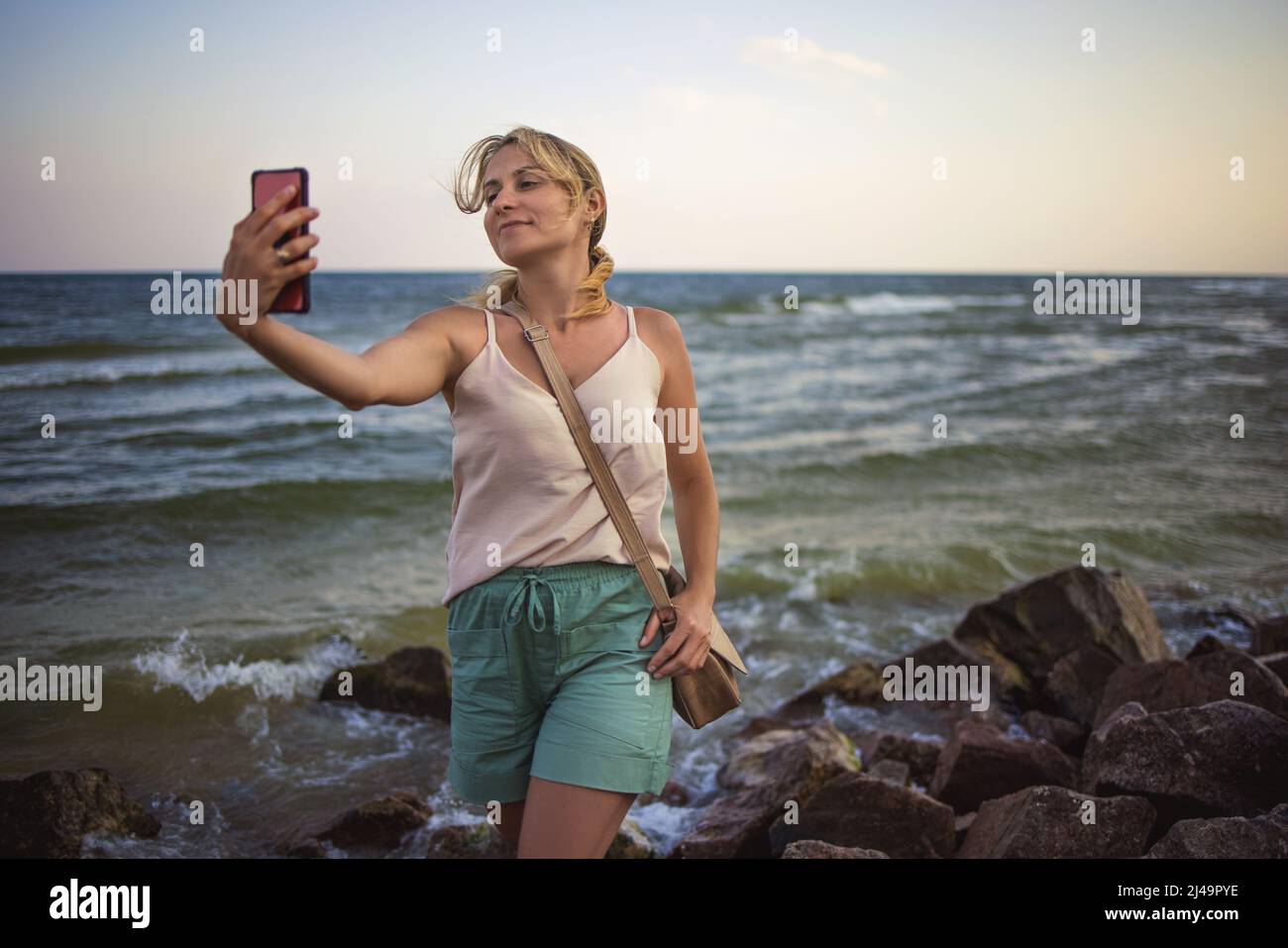 Beautiful happy young woman in mild light clothes with a careful braid ...
