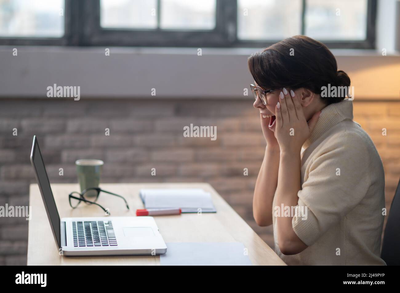 An excited woman sitting at the laptop and looking surprised Stock ...