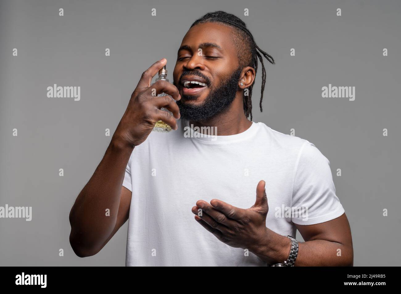 Male with closed eyes spraying himself with cologne Stock Photo - Alamy