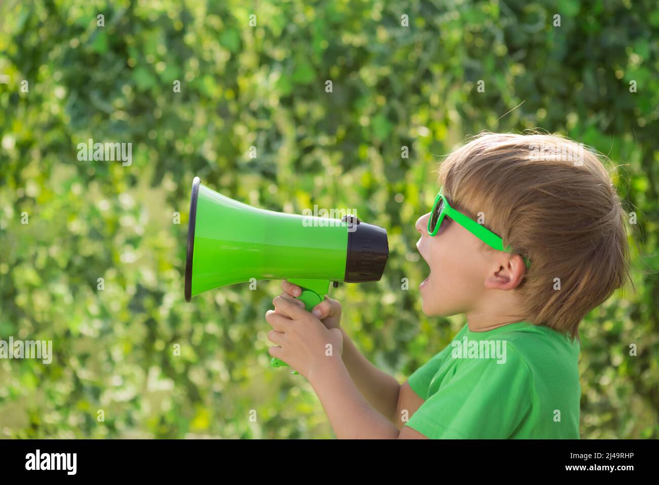 Happy child shouting through loudspeaker. Portrait of kid outdoor. Boy ...