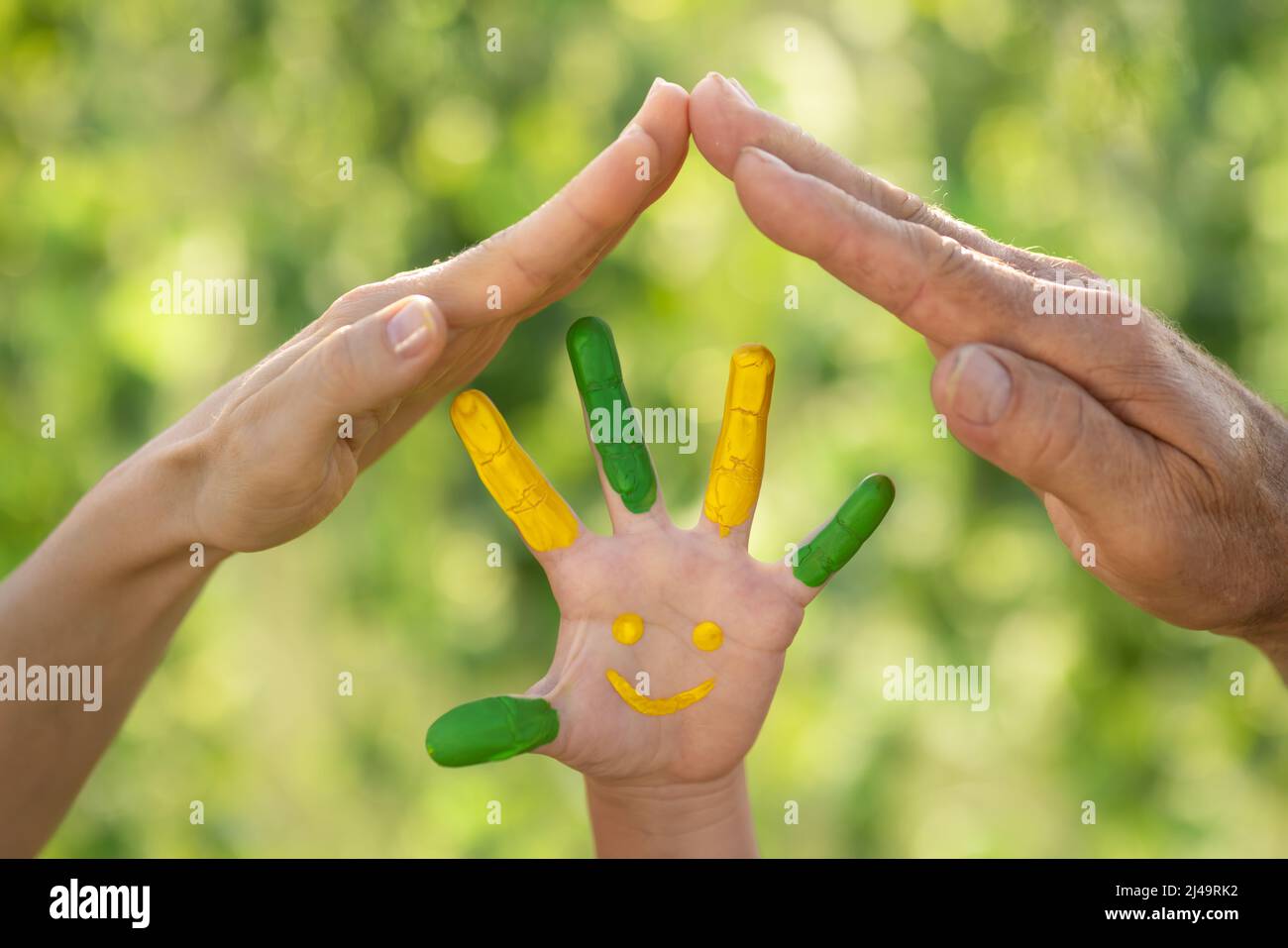 Happy child with smile on hand against green spring background. Family ...
