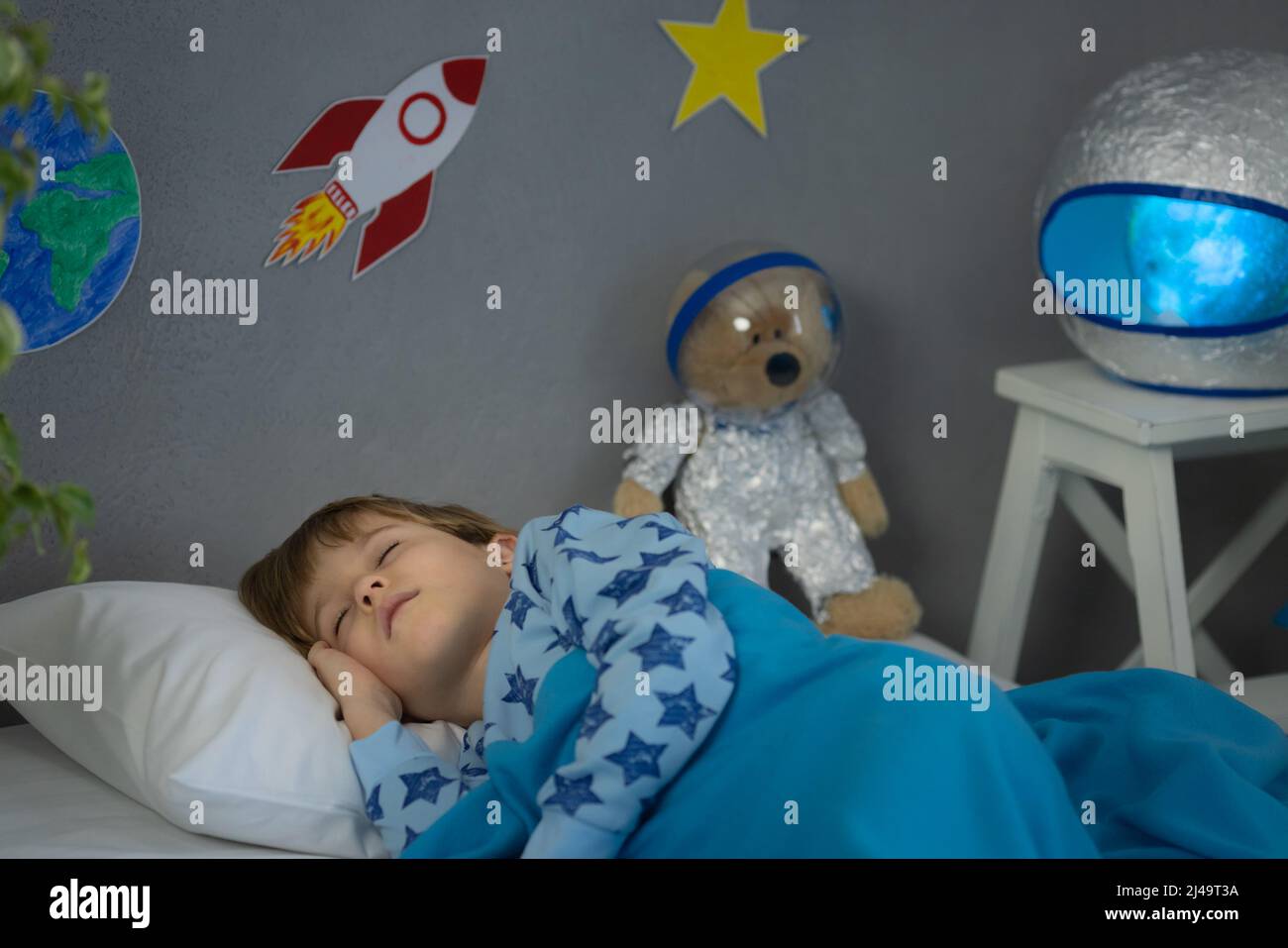 Happy child sleeping with toy rocket and teddy bear. Kid pretend to be ...