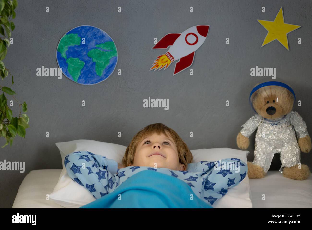 Happy child sleeping with toy rocket and teddy bear. Kid pretend to be ...