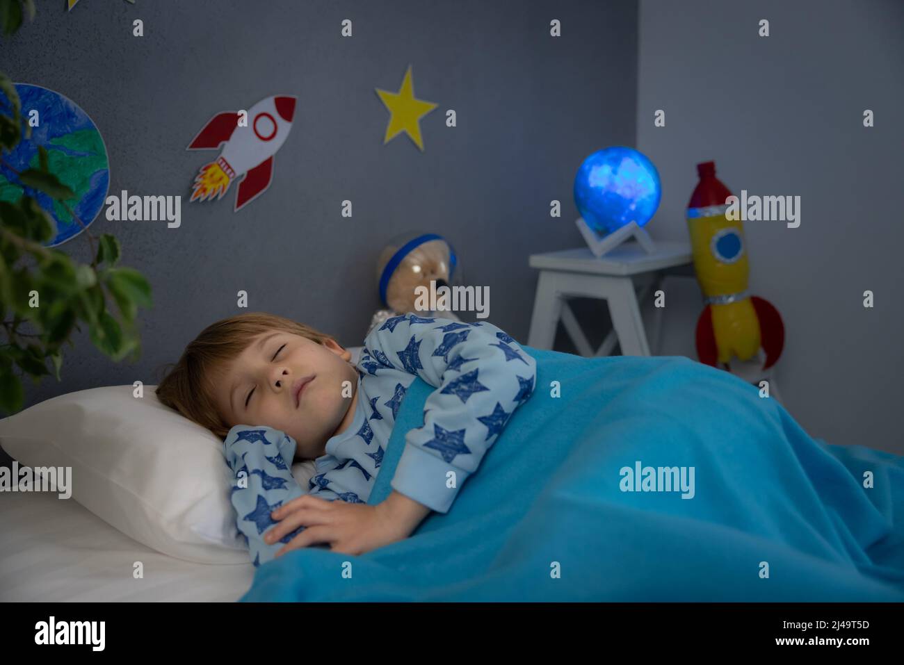 Happy child sleeping with toy rocket and teddy bear. Kid pretend to be ...