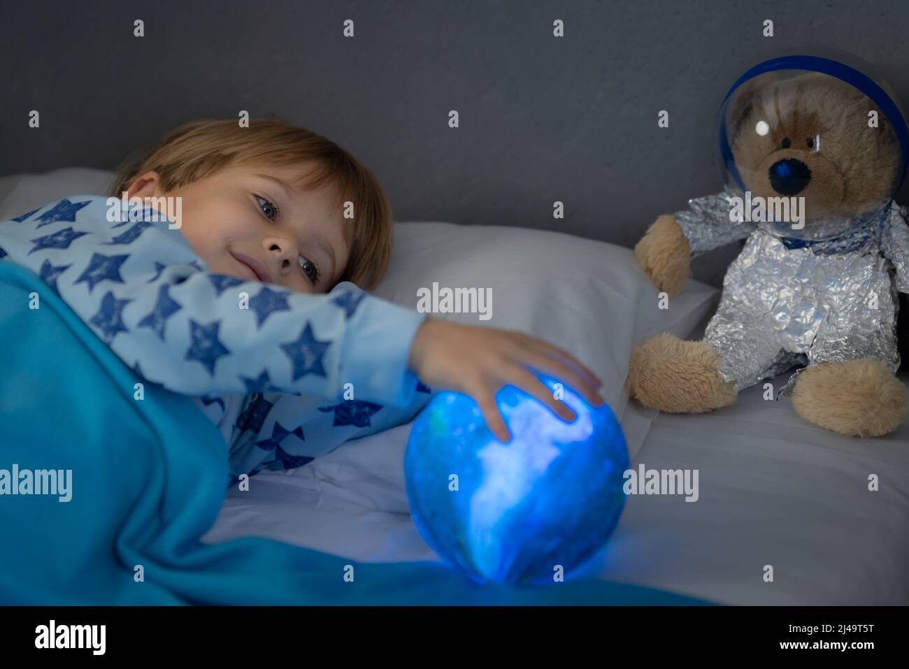 Happy child sleeping with toy rocket and teddy bear. Kid pretend to be ...