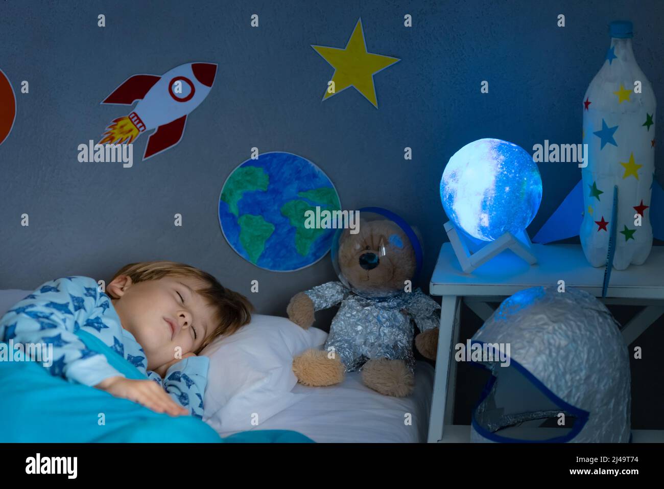 Happy child sleeping with toy rocket and teddy bear. Kid pretend to be ...