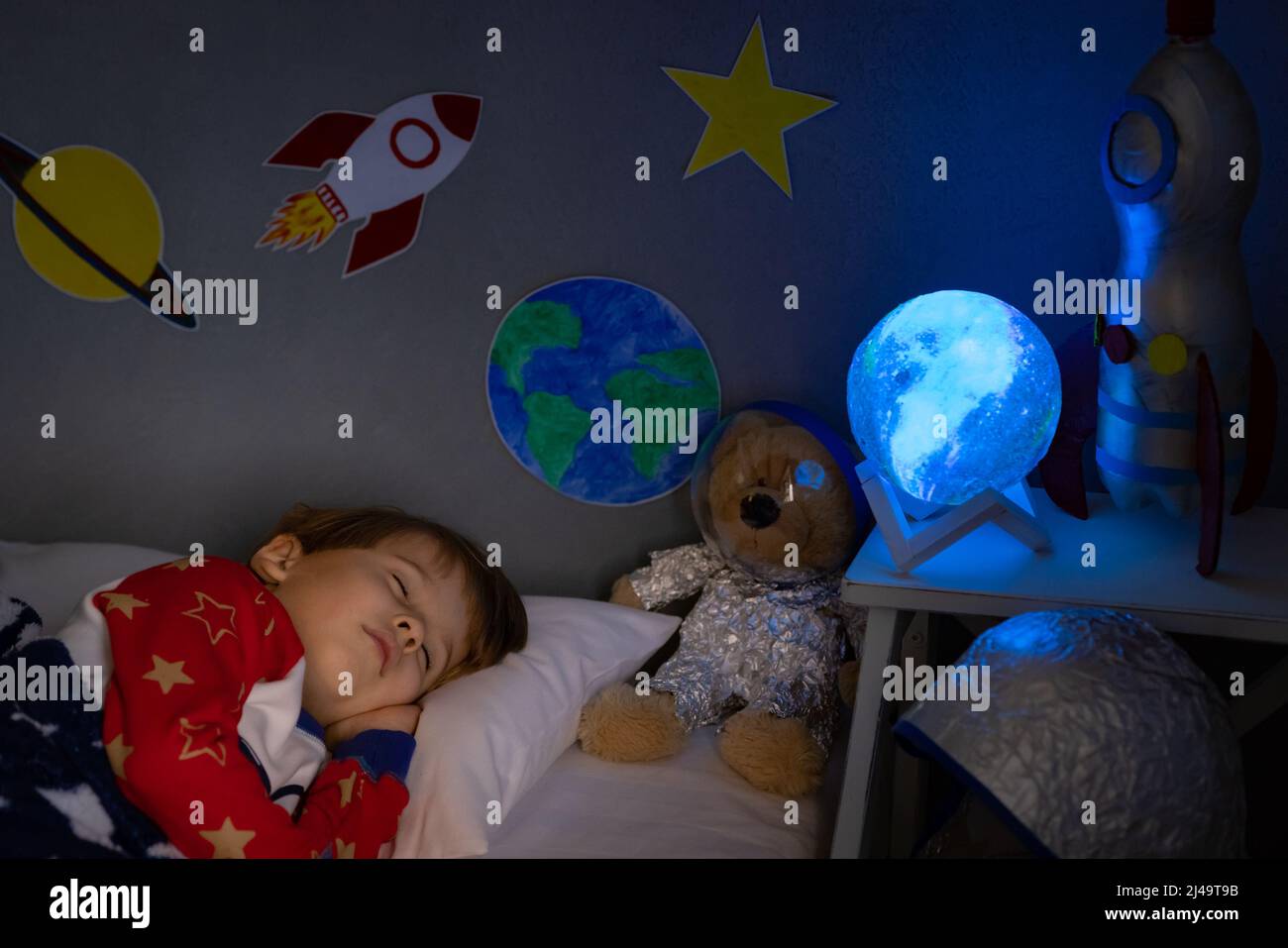Happy child sleeping with toy rocket and teddy bear. Kid pretend to be ...
