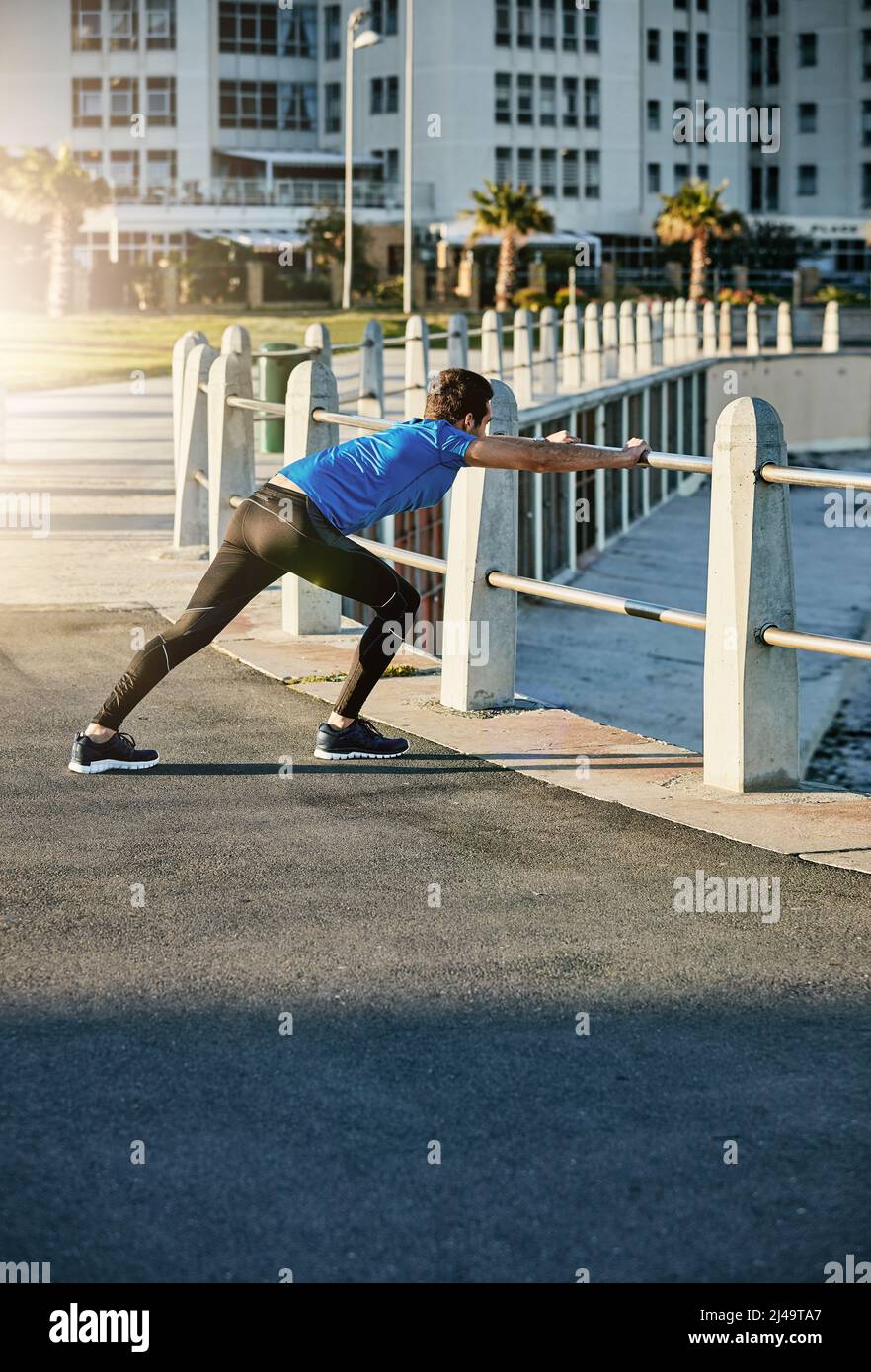 Getting ready for that run. Shot of a young man stretching outside ...
