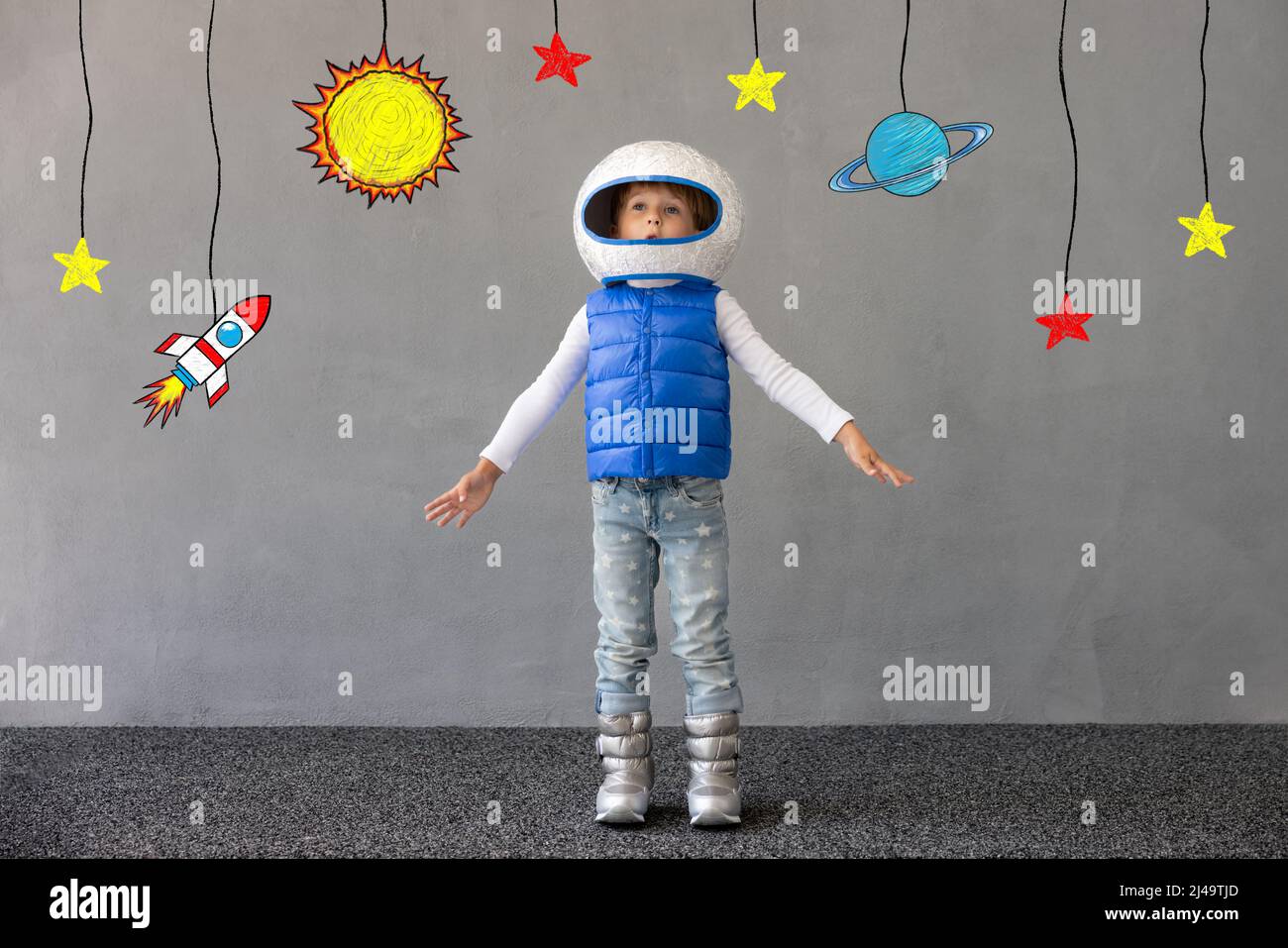 Happy child playing with toy rocket against concrete wall background ...