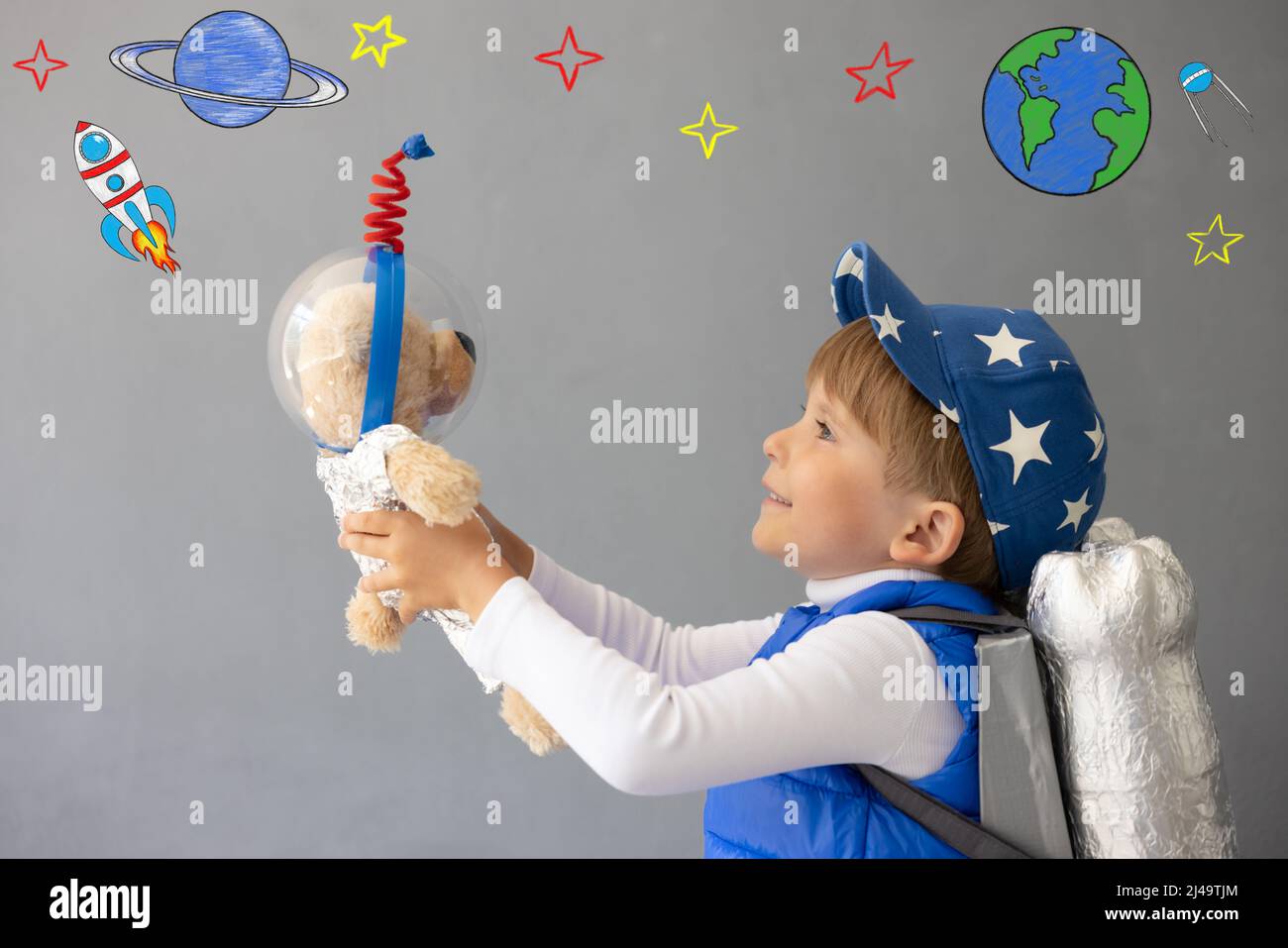 Happy child playing with toy rocket. Kid holding teddy bear against ...
