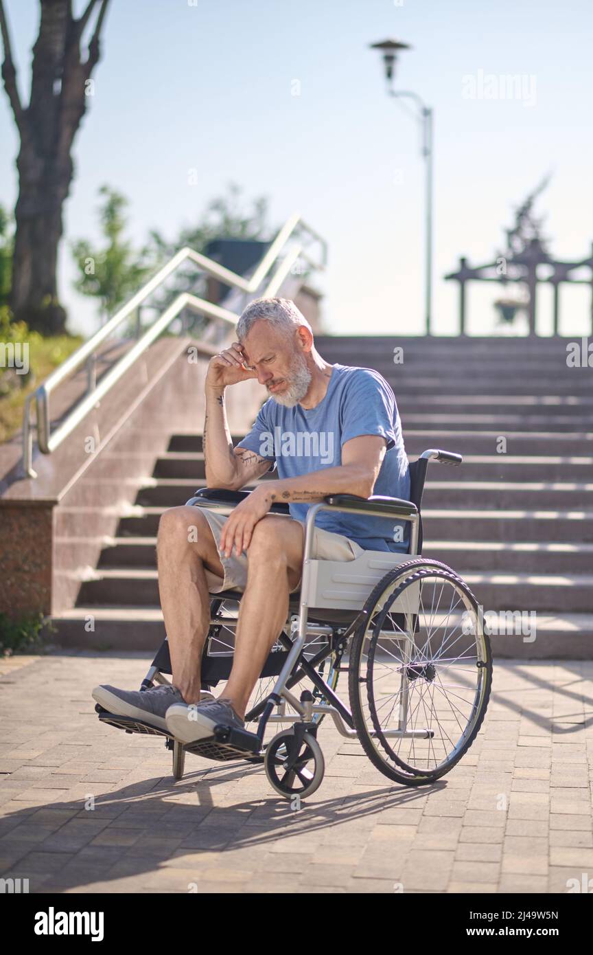 A disabled man in a wheel chair outdoors looking thoughtful Stock Photo ...