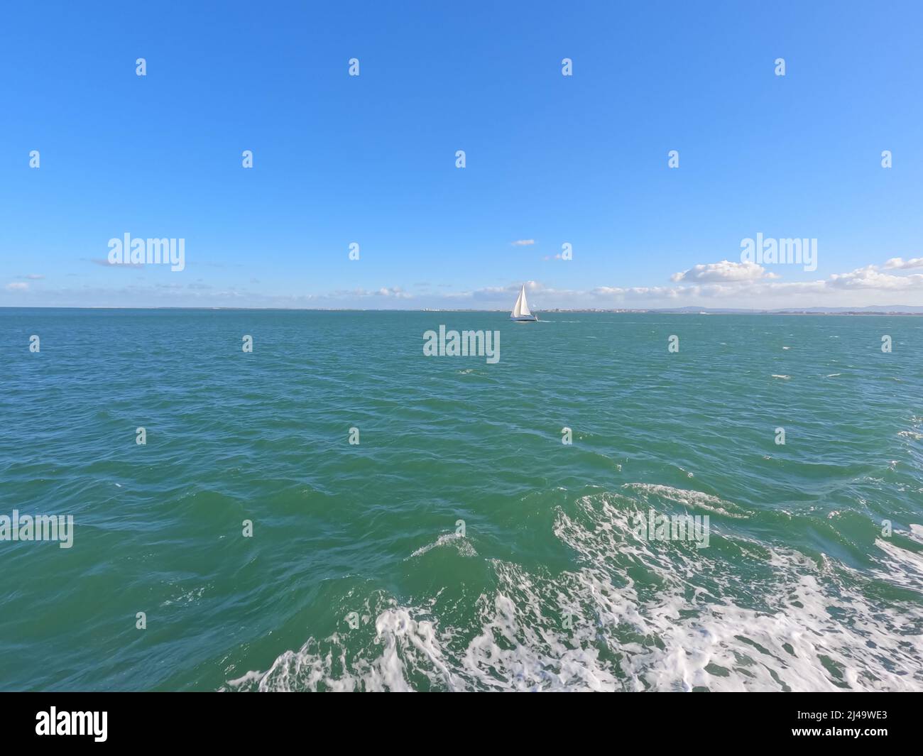 Little boat in the middle of the blue sea with the horizon and blue sky ...