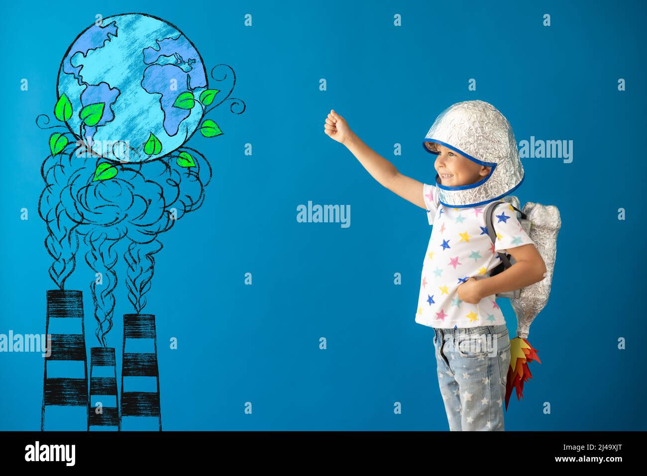 Happy child playing with toy rocket against blue background. Kid ...
