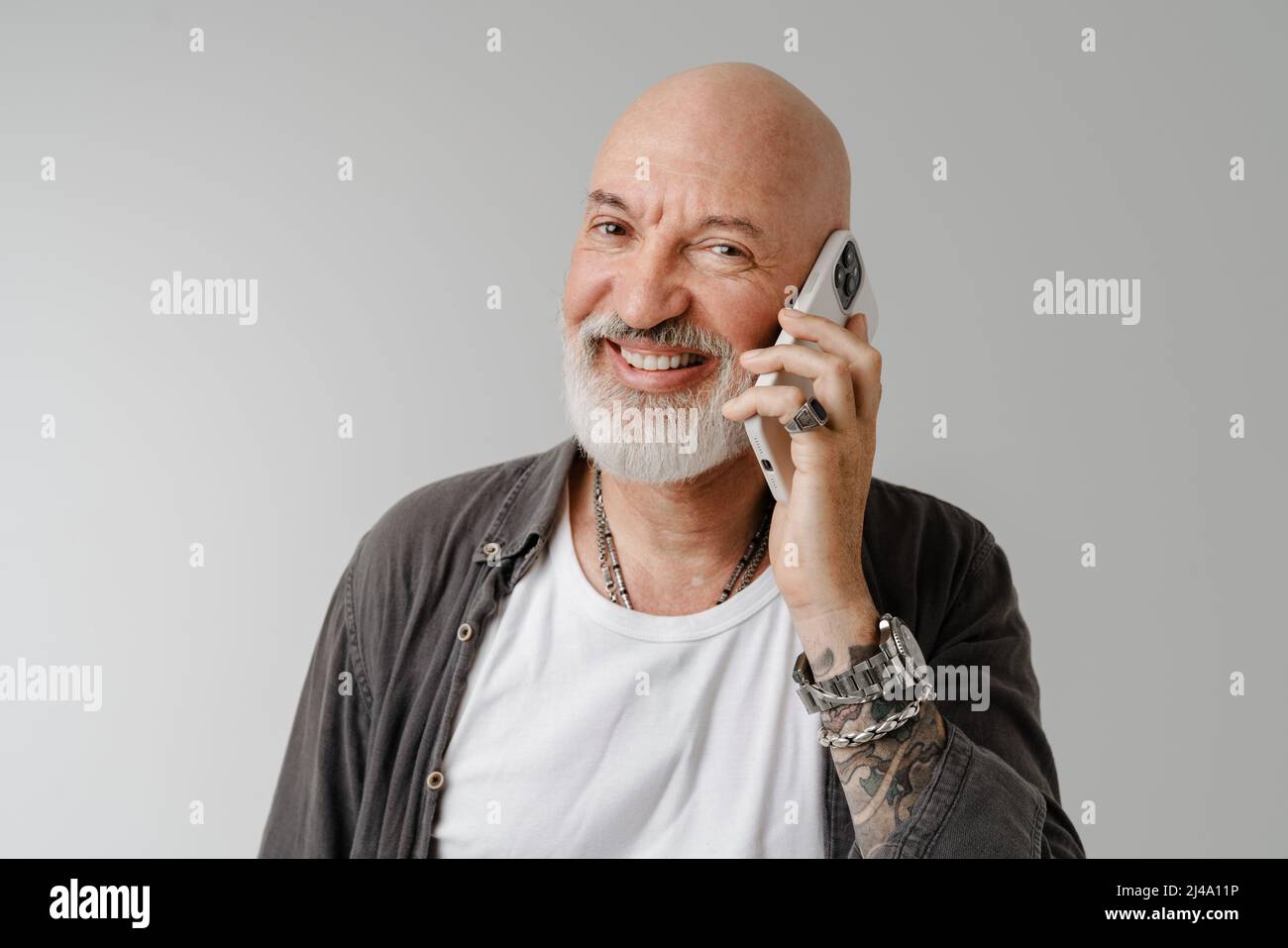 Bald european man with beard talking on using mobile phone isolated ...