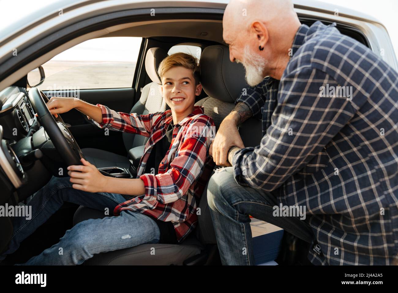 Happy middle aged father and his preschooler son sitting in a car ...