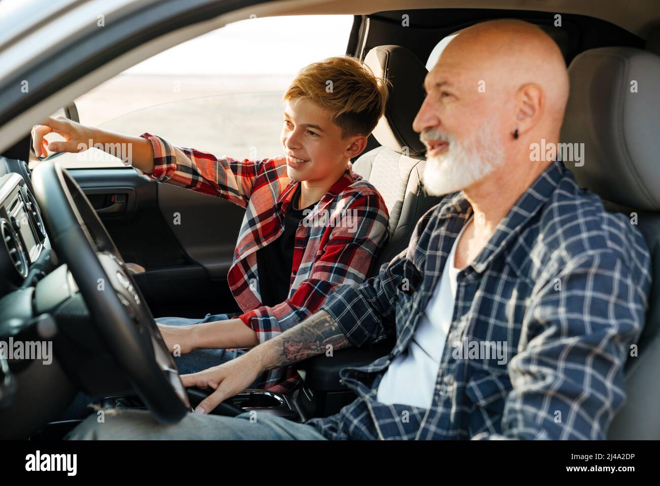 Happy middle aged father and his preschooler son sitting in a car ...