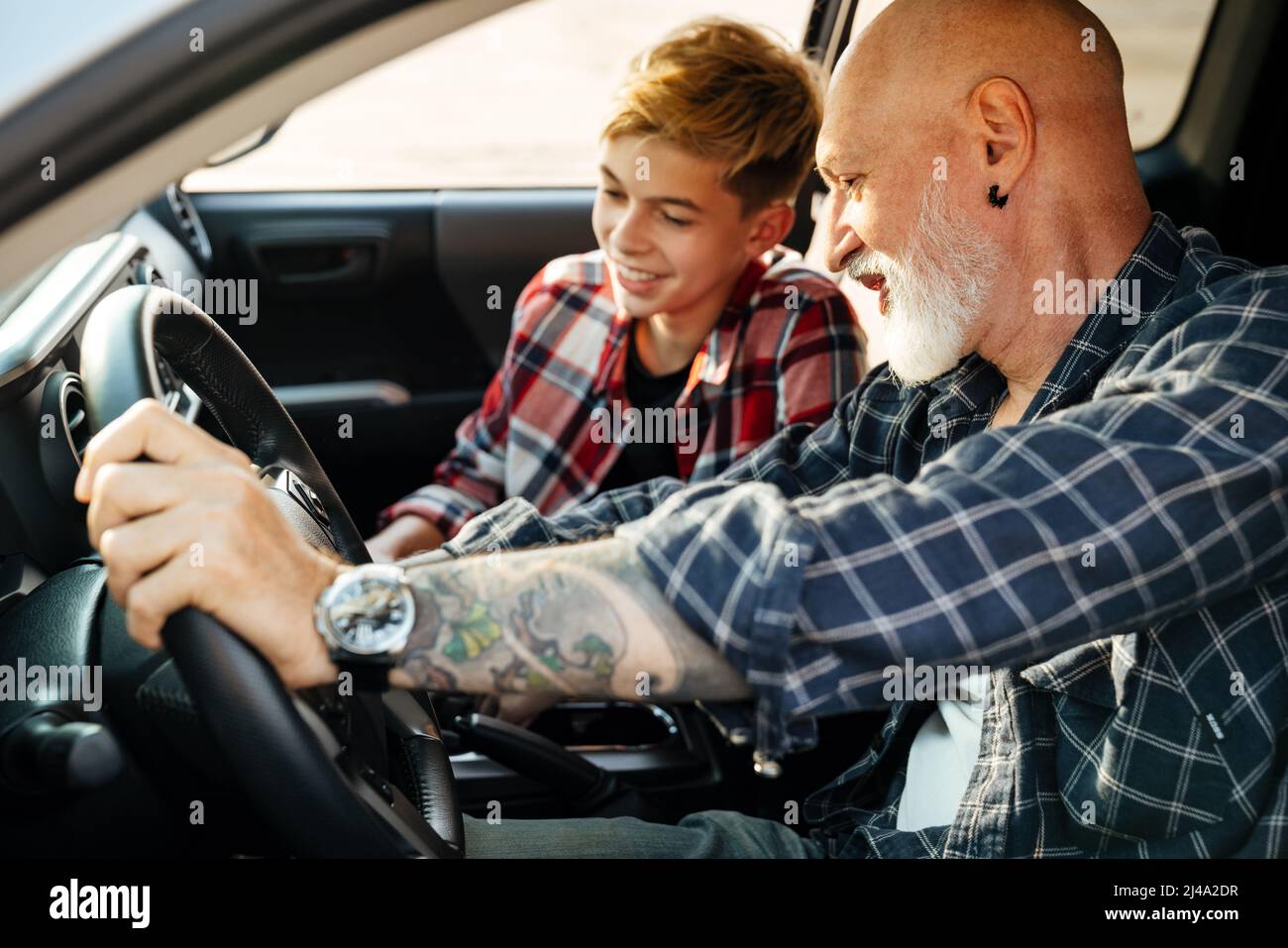 Happy middle aged father and his preschooler son sitting in a car ...