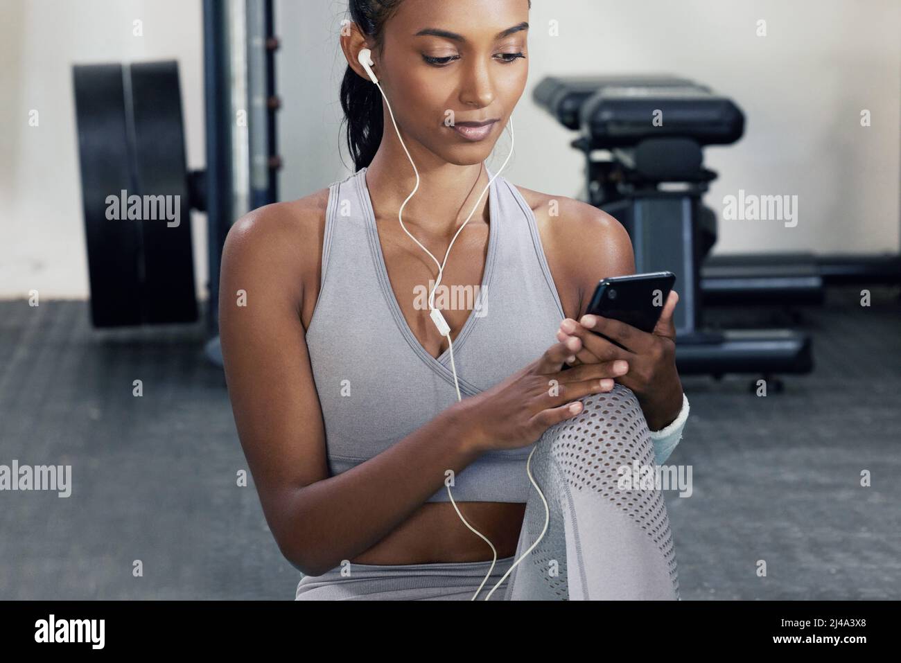 Compiling a playlist of the best tracks for her workout. Shot of a ...