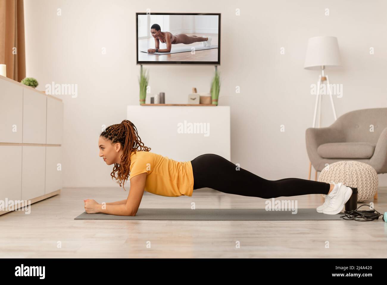 Female Doing Plank Watching Sport Channel On TV At Home Stock Photo - Alamy