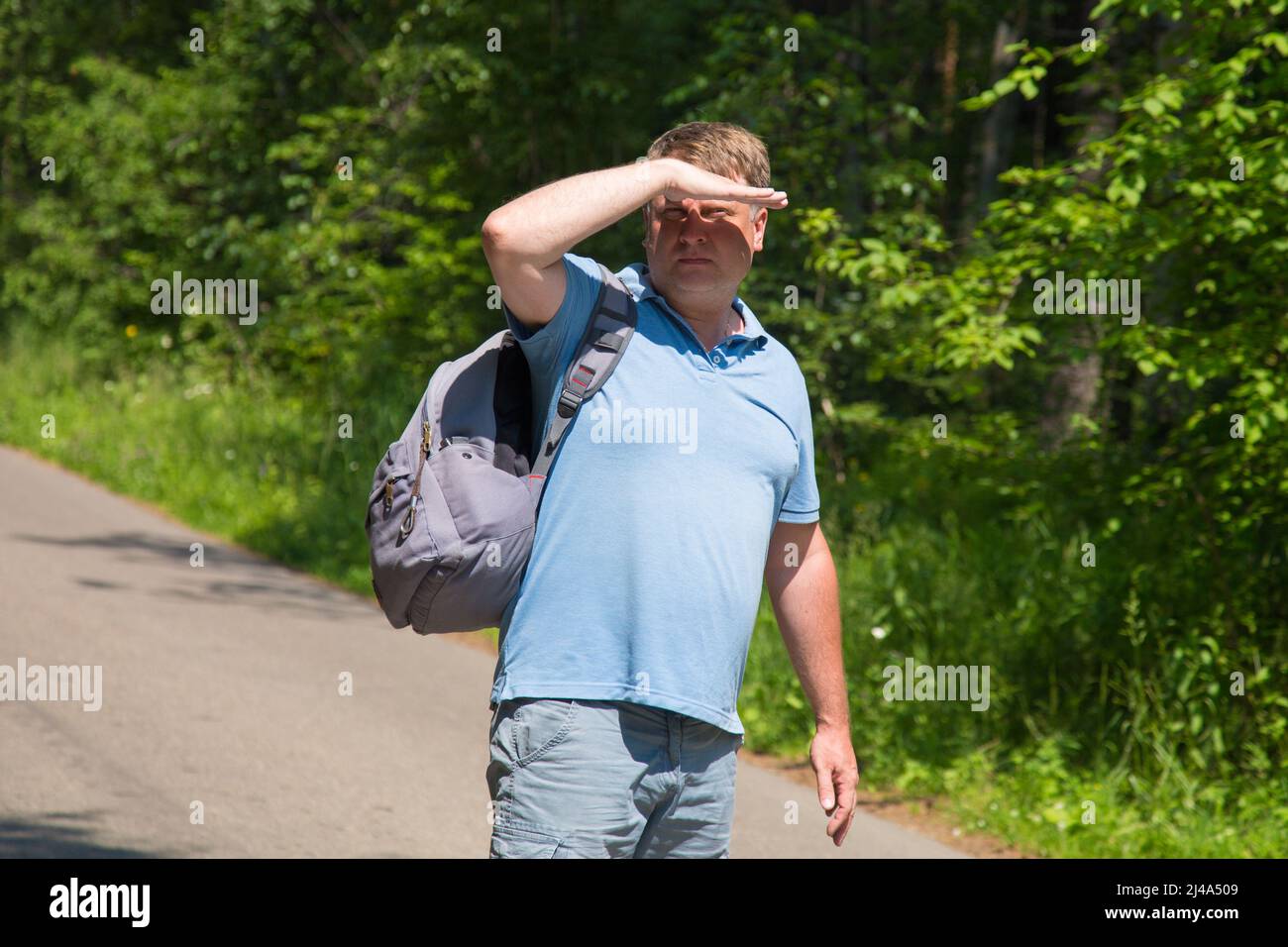 A lost tourist with a backpack on his shoulder looks into the distance ...