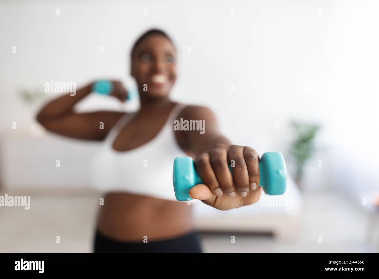 Plus size young black woman doing exercises with dumbbells ...