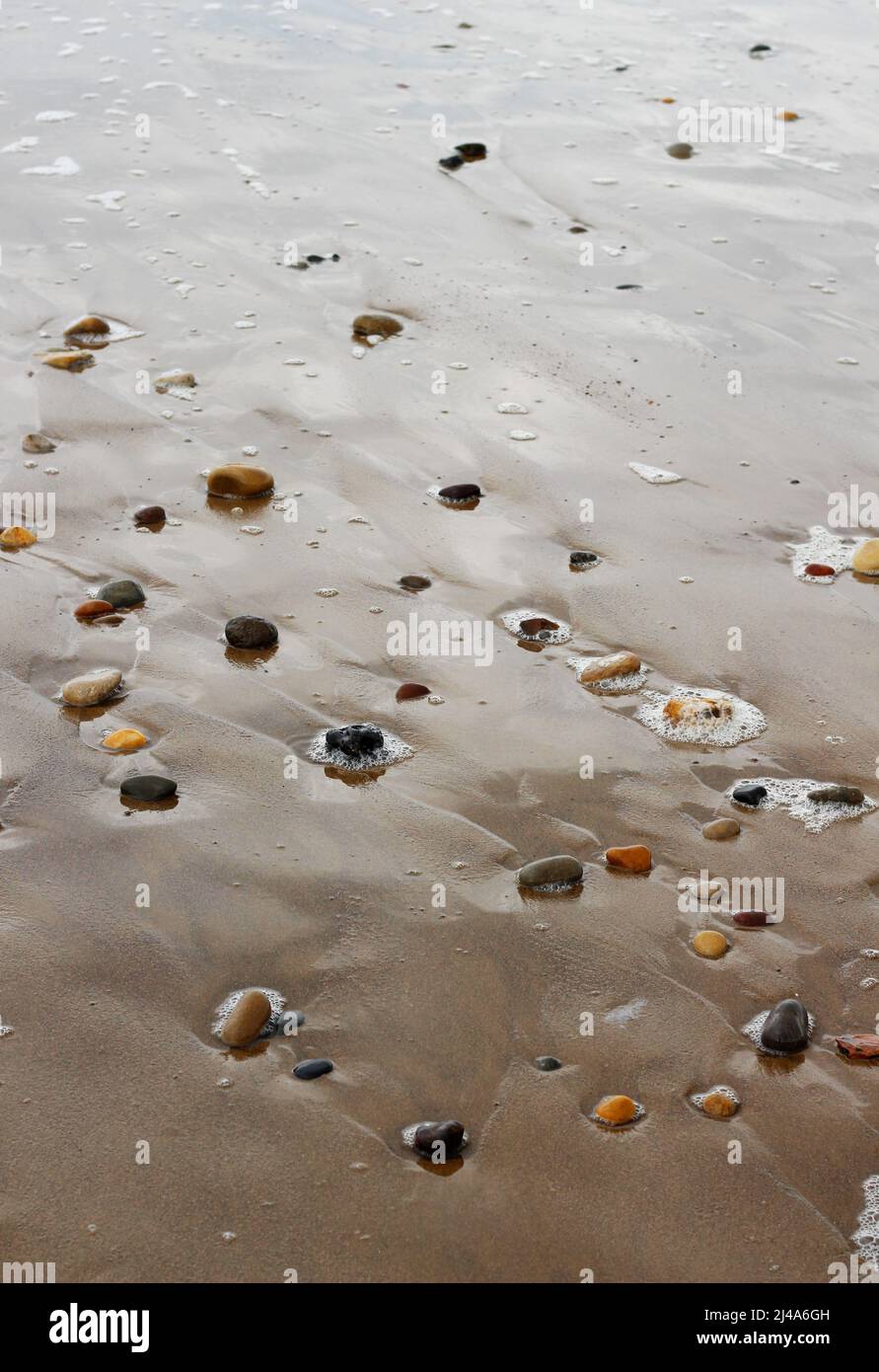 Pebbles of various types, shapes and sizes in the sand. Sandsend beach ...