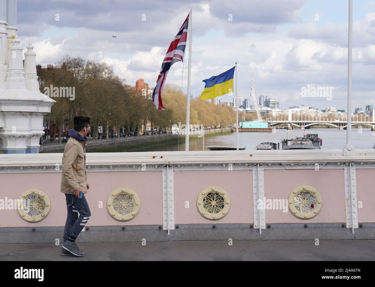 A man walks across Albert Bridge as a Ukrainian flag (right) is flying ...