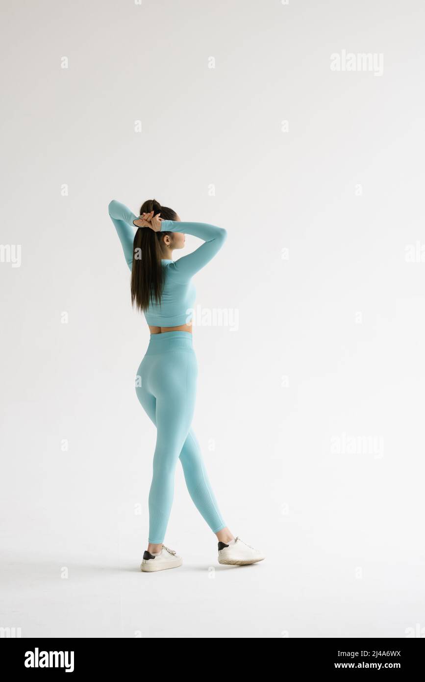 Young sporty beautiful woman stretching arms on side over white ...