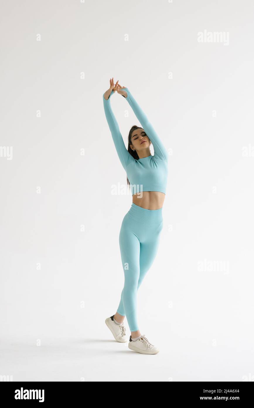 Young sporty beautiful woman stretching arms on side over white ...