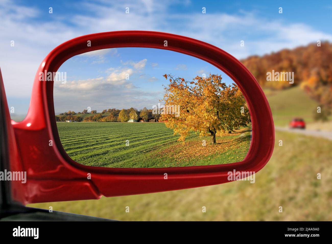 Landscape reflected in the rear view mirror of a red car - autumn ...