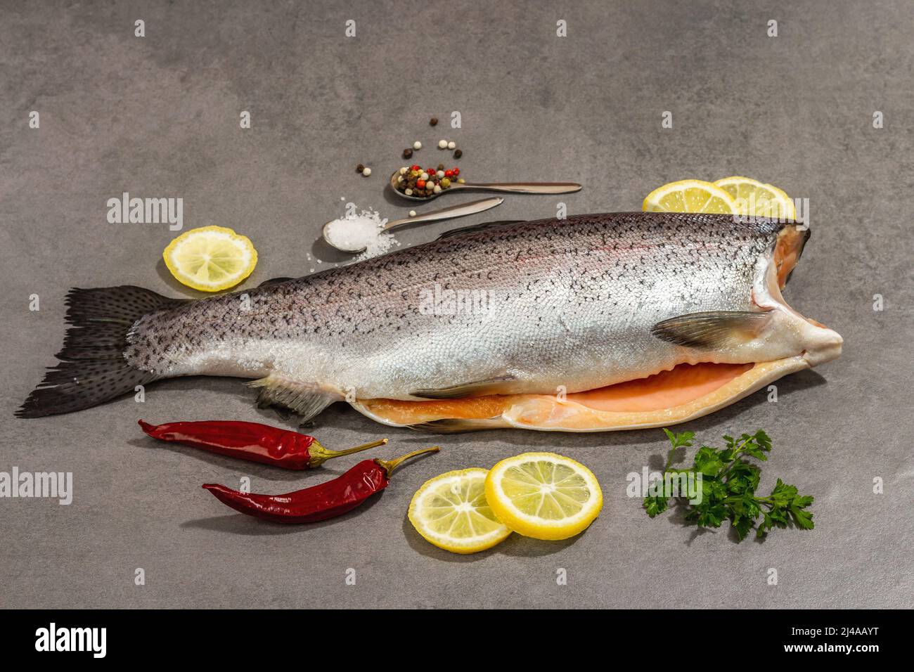Raw trout carcass with spices and herbs on a grey stone concrete ...