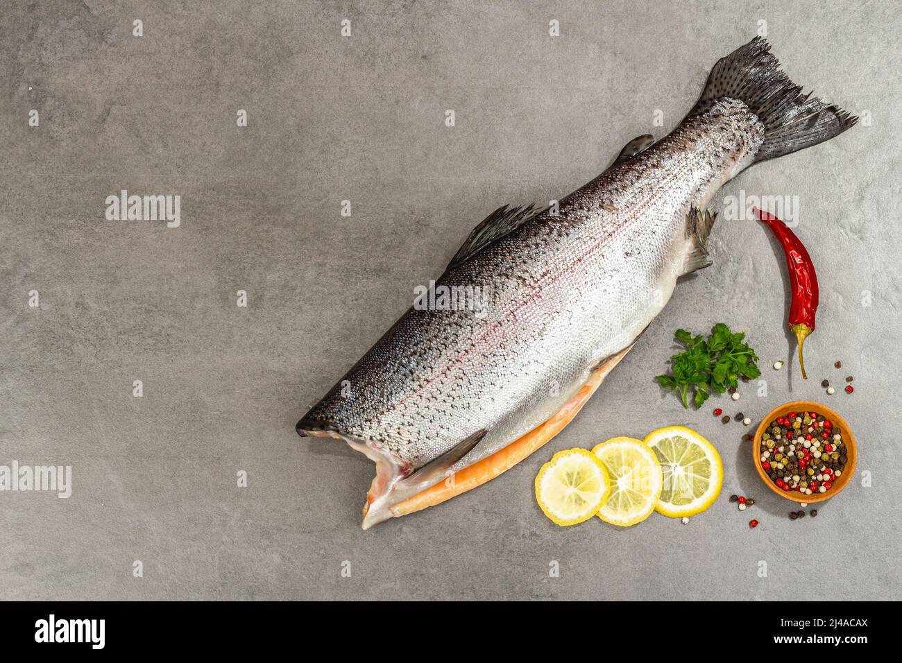 Raw trout carcass with spices and herbs on a grey stone concrete ...