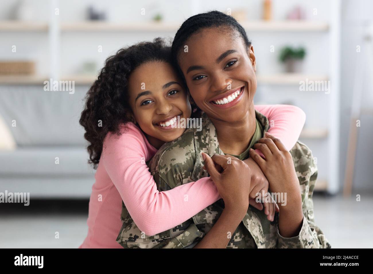 Portrait of cheerful black teen girl hugging her mother soldier Stock ...