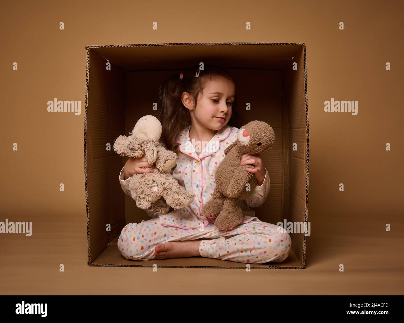 Charming little girl plays with her plush toys while sitting inside a ...