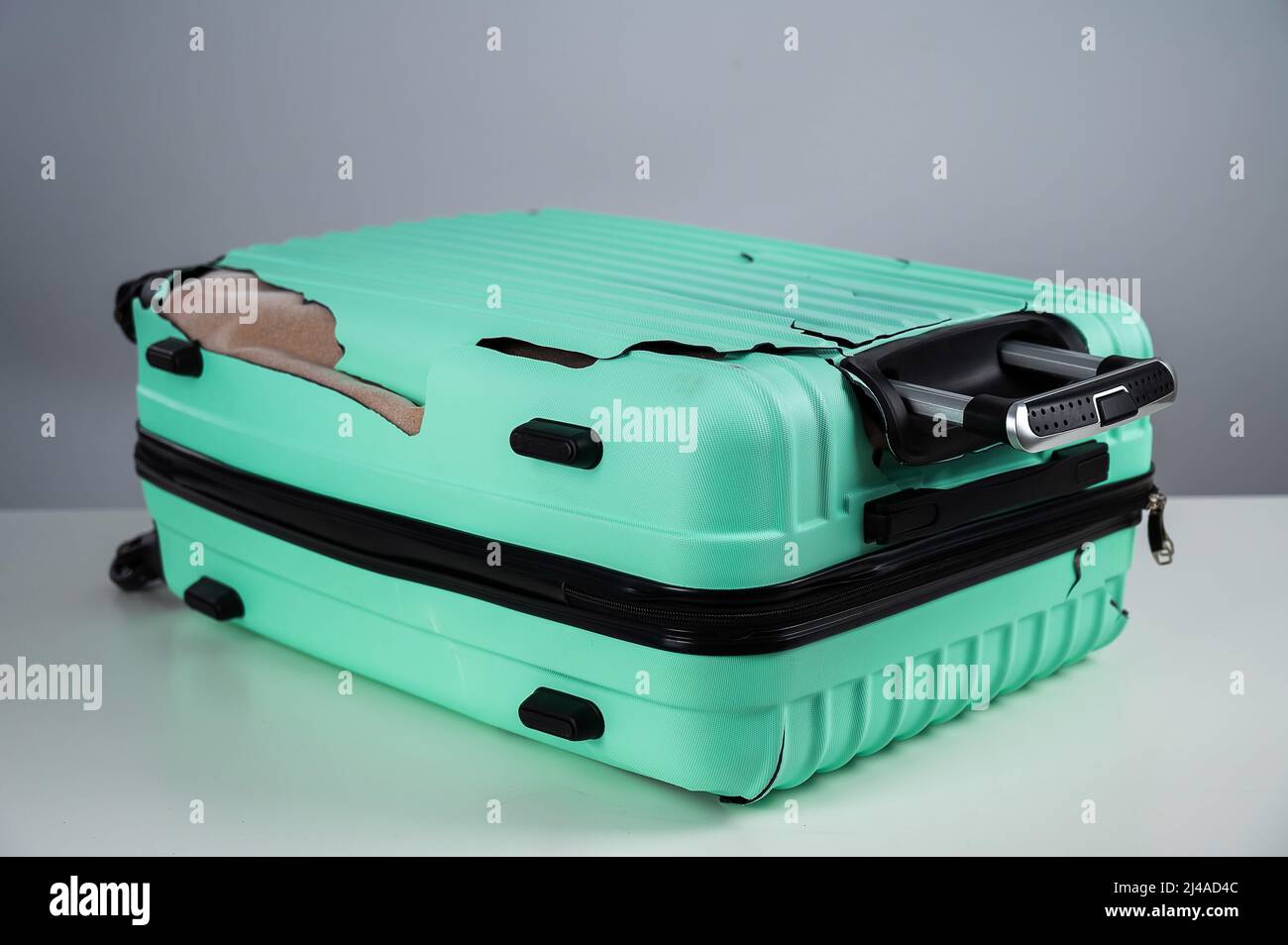 Broken plastic mint suitcase on a white background Stock Photo - Alamy