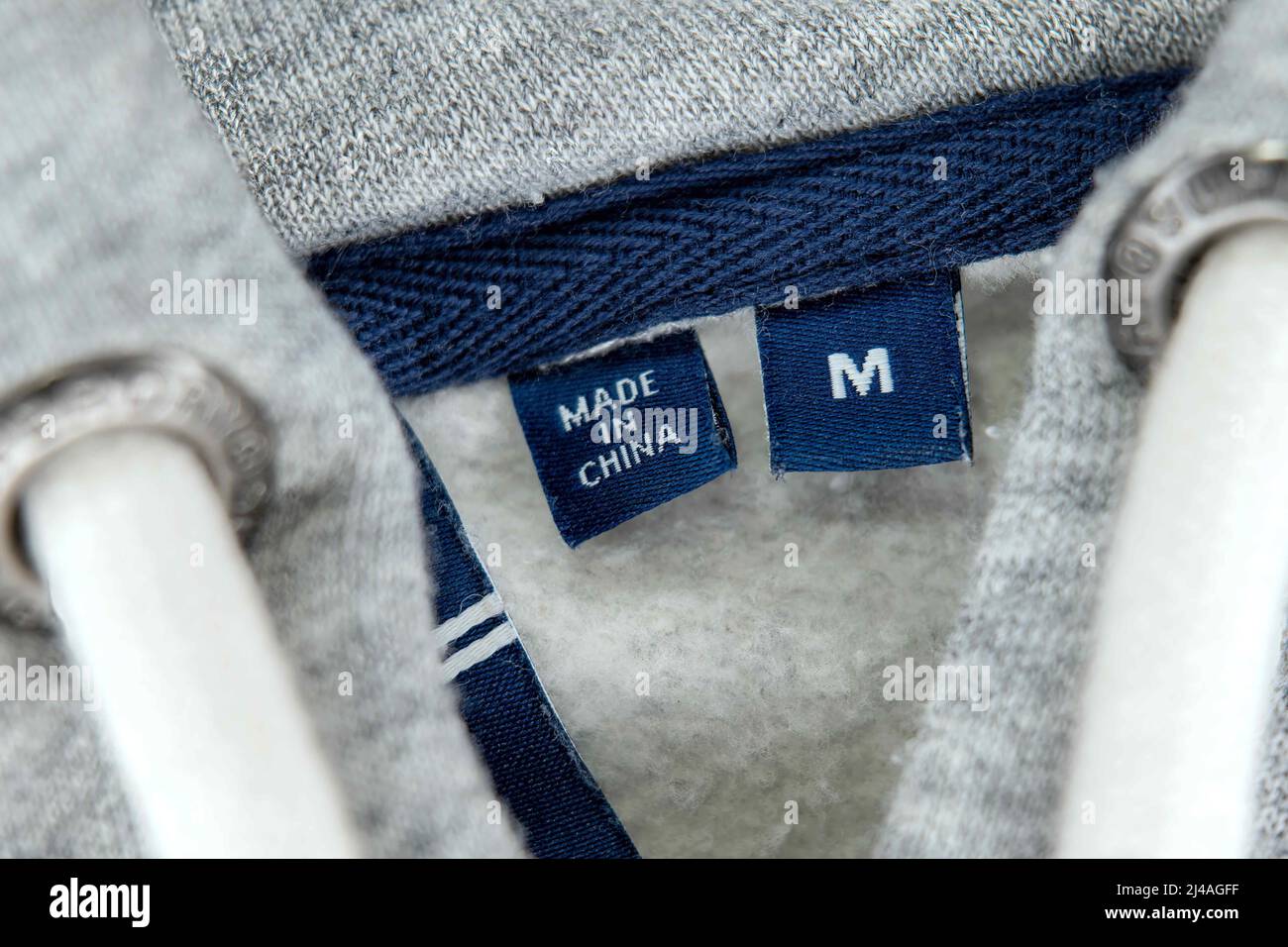 Hoodie, gray with blue labels "Made In China" and "M Stock Photo - Alamy