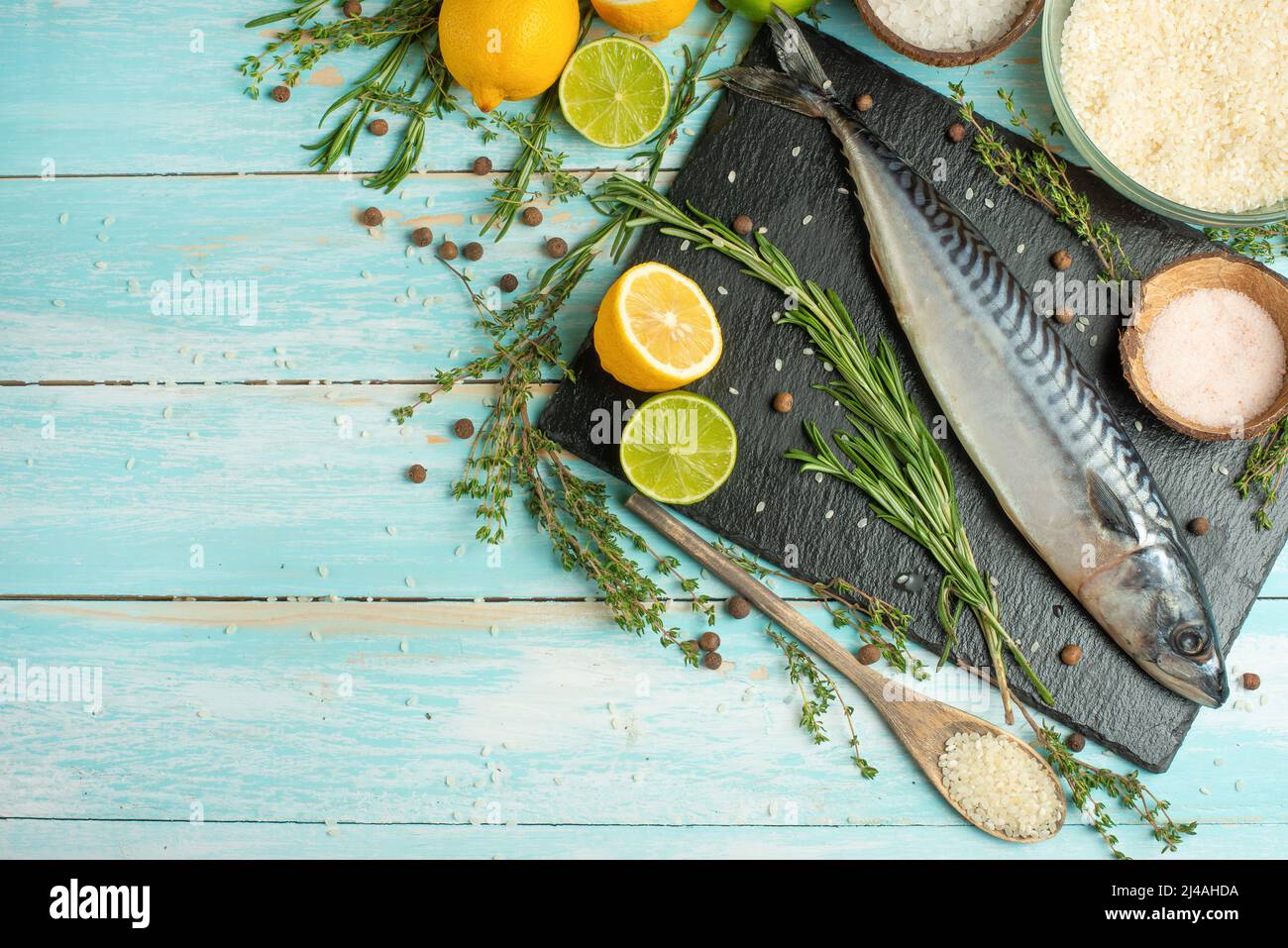 Fresh mackerel on a black slate stone with spices, herbs, lemon, lime ...