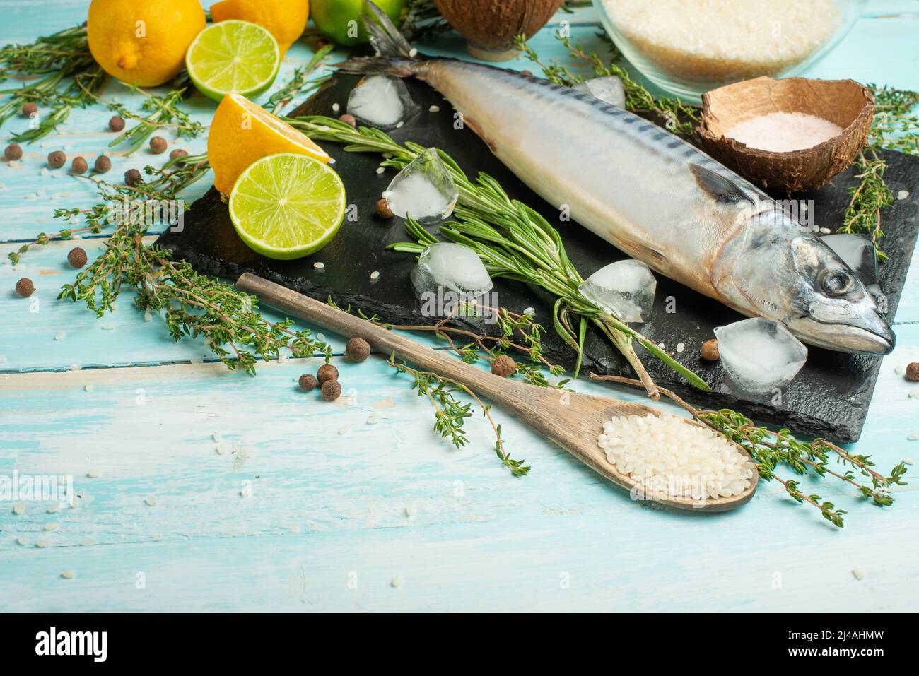 Fresh mackerel on a black slate stone with spices, herbs, lemon, lime ...