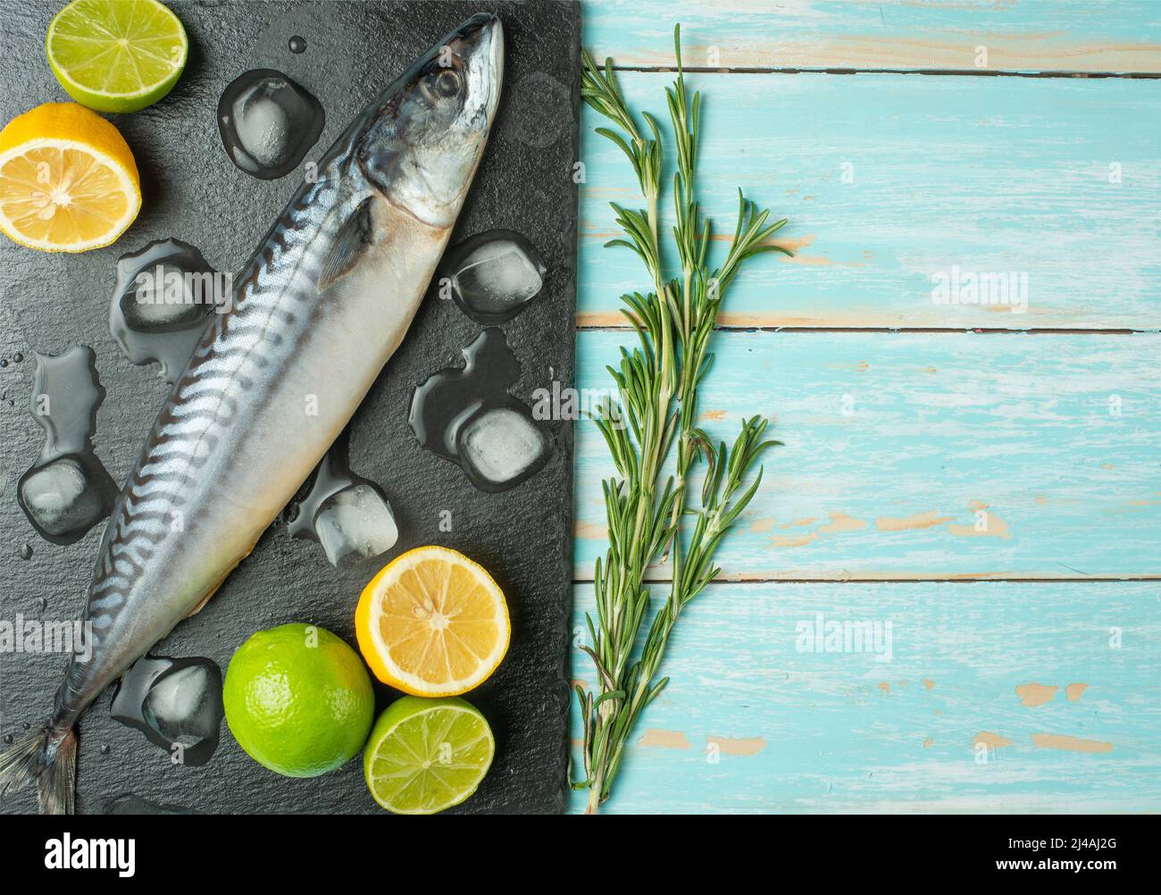 Fresh mackerel on a black slate stone with spices, herbs, lemon, lime ...