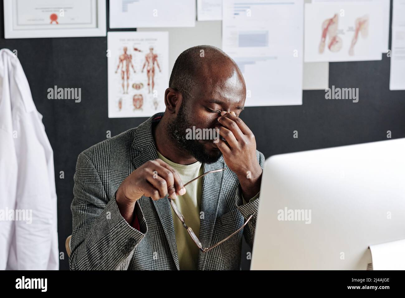 African man rubbing his eyes tired of his work on computer while ...