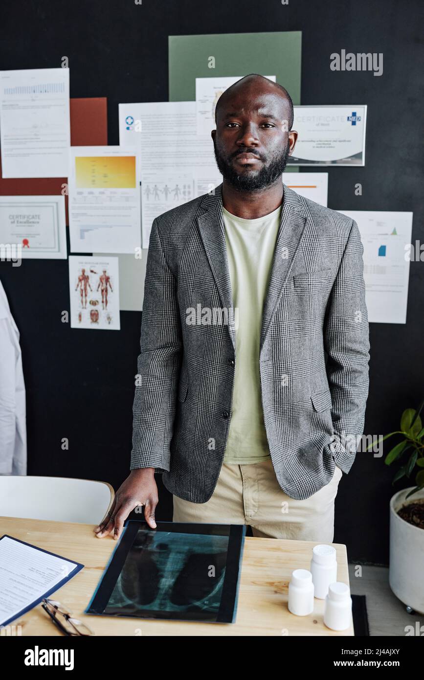 Portrait of African male radiologist in jacket looking at camera while ...