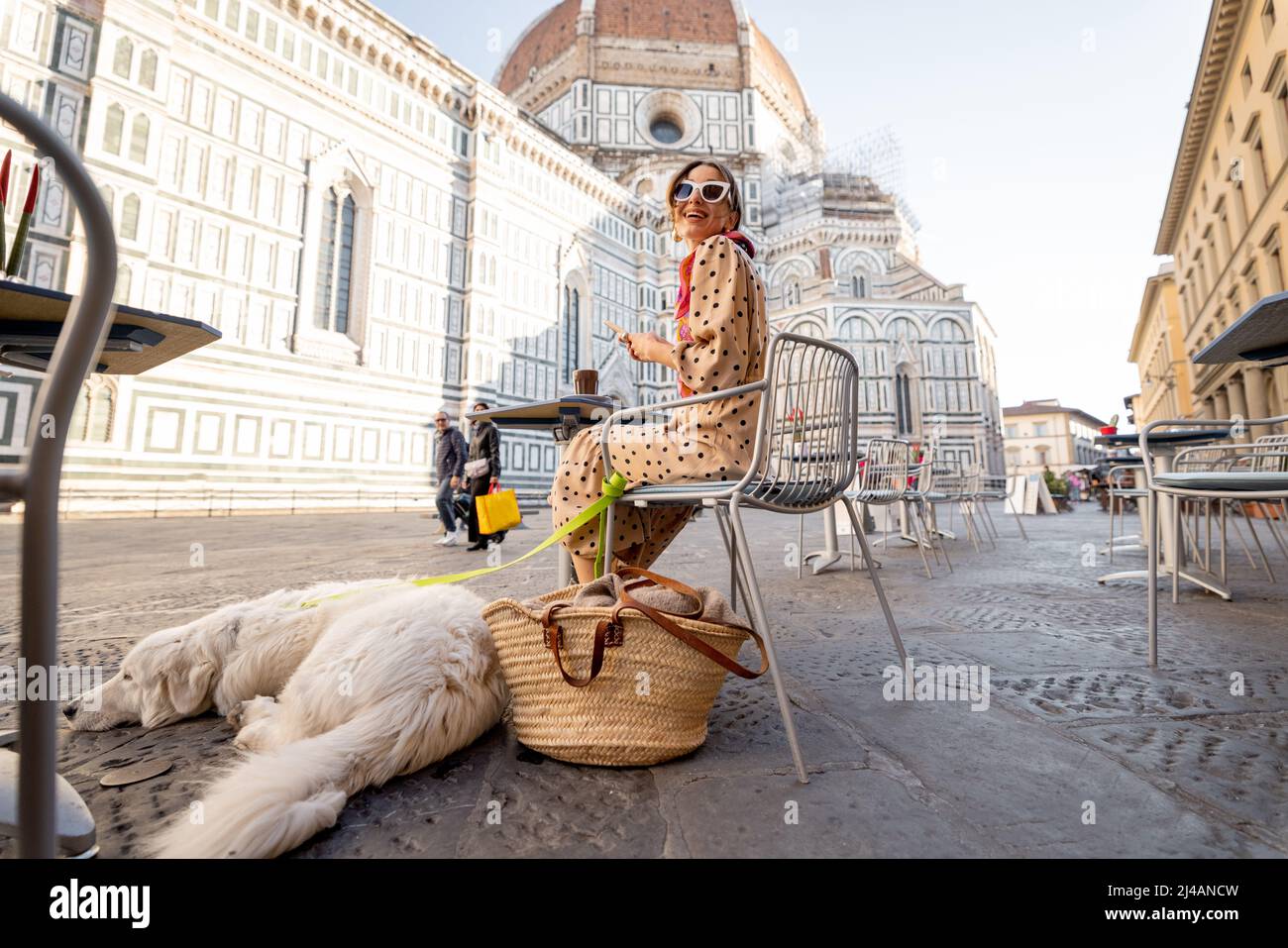 Woman sitting with her dog on cafe terrace near famous Duomo cathedral ...