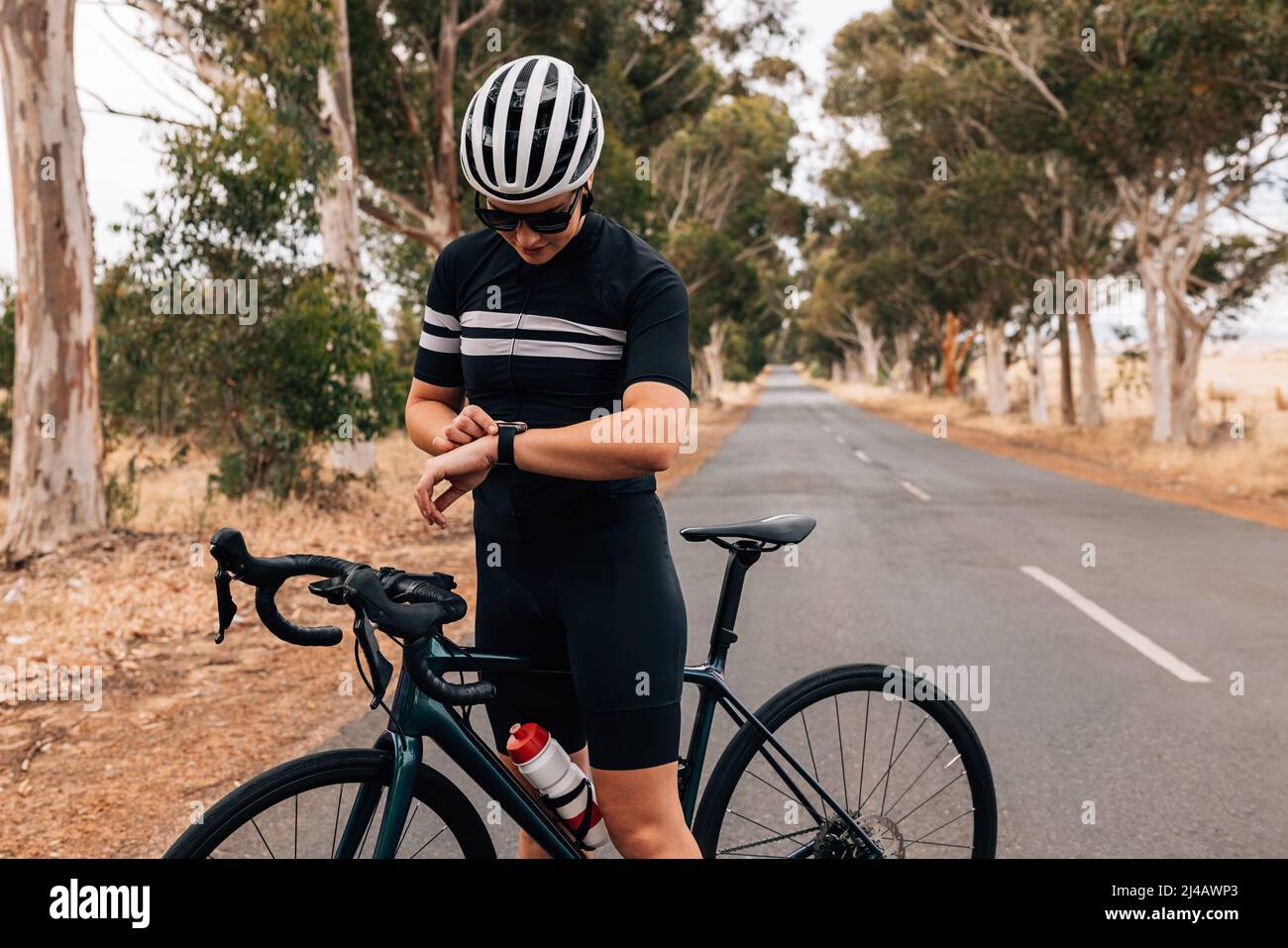 Young cyclist woman in sportswear checking smartwatch during training ...